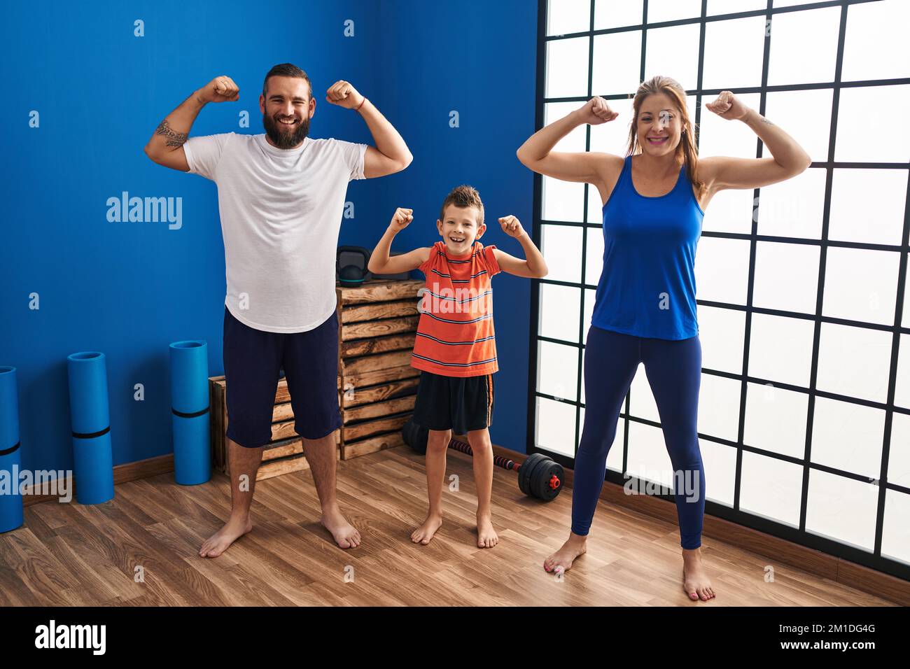 Family of three wearing sportswear at the gym smiling and laughing hard ...