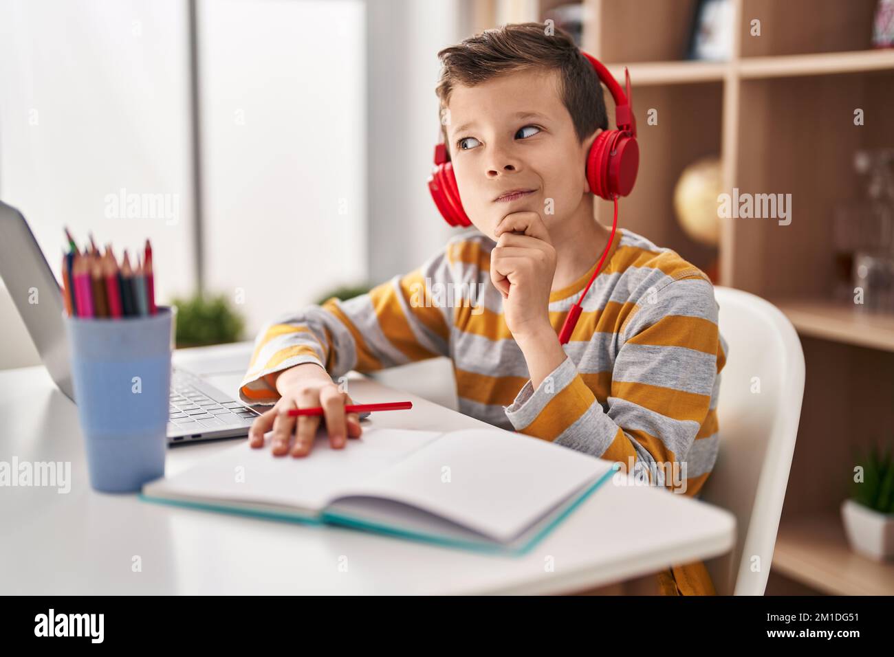 Young caucasian kid doing homework at home serious face thinking about ...
