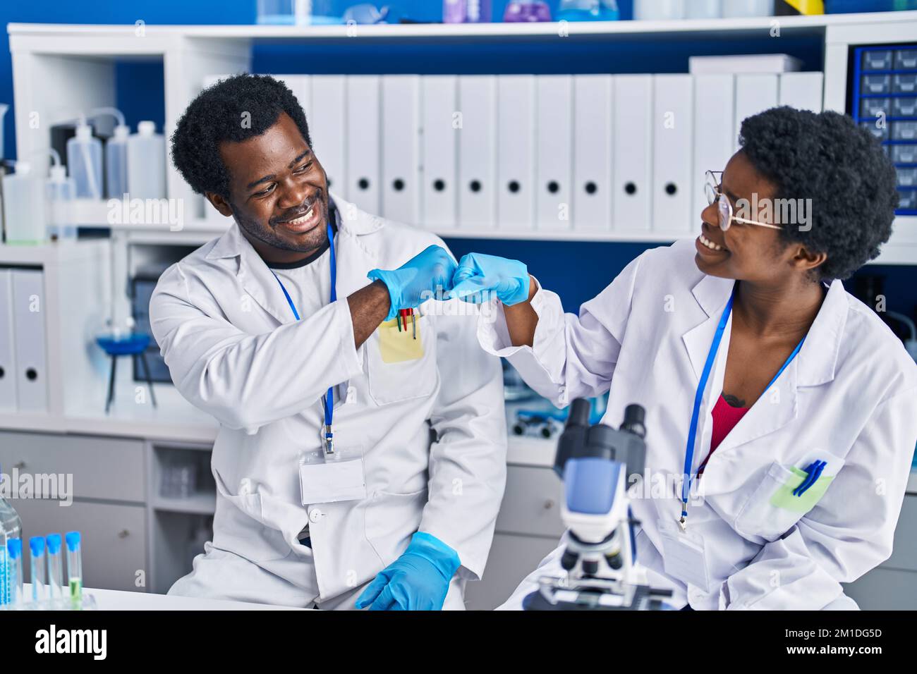 African american man and woman scientists bump fists at laboratory Stock Photo - Alamy