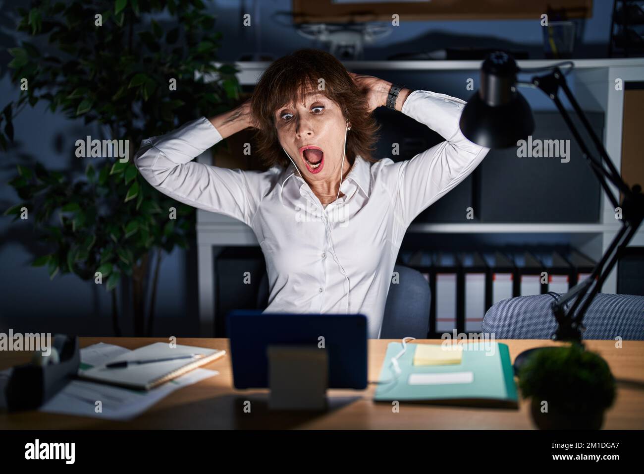 Middle age woman working at the office at night crazy and scared with ...