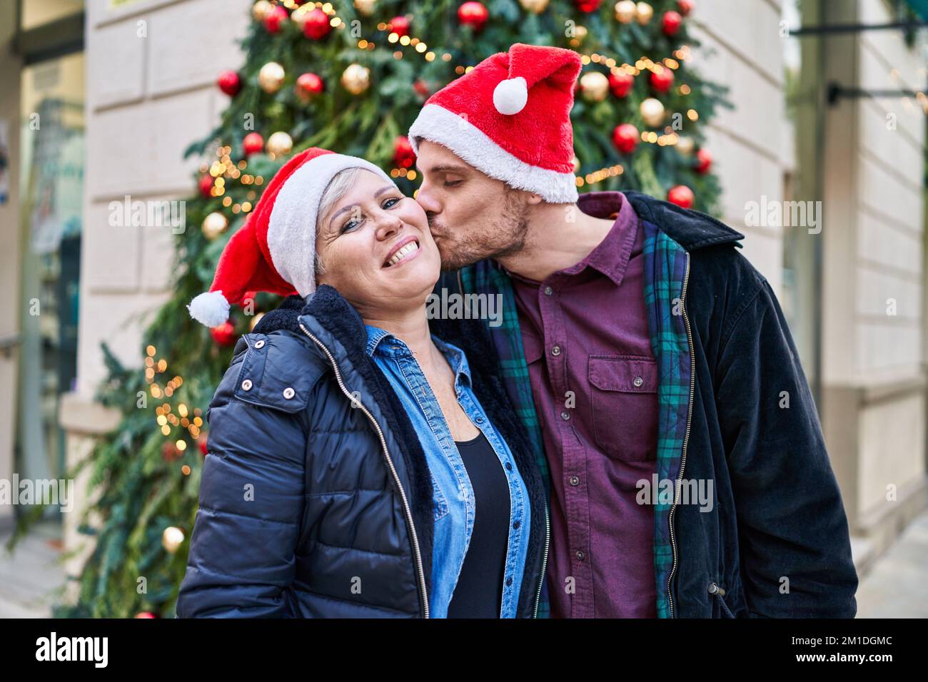Mother and son smiling confident standing by christmas tree at street ...