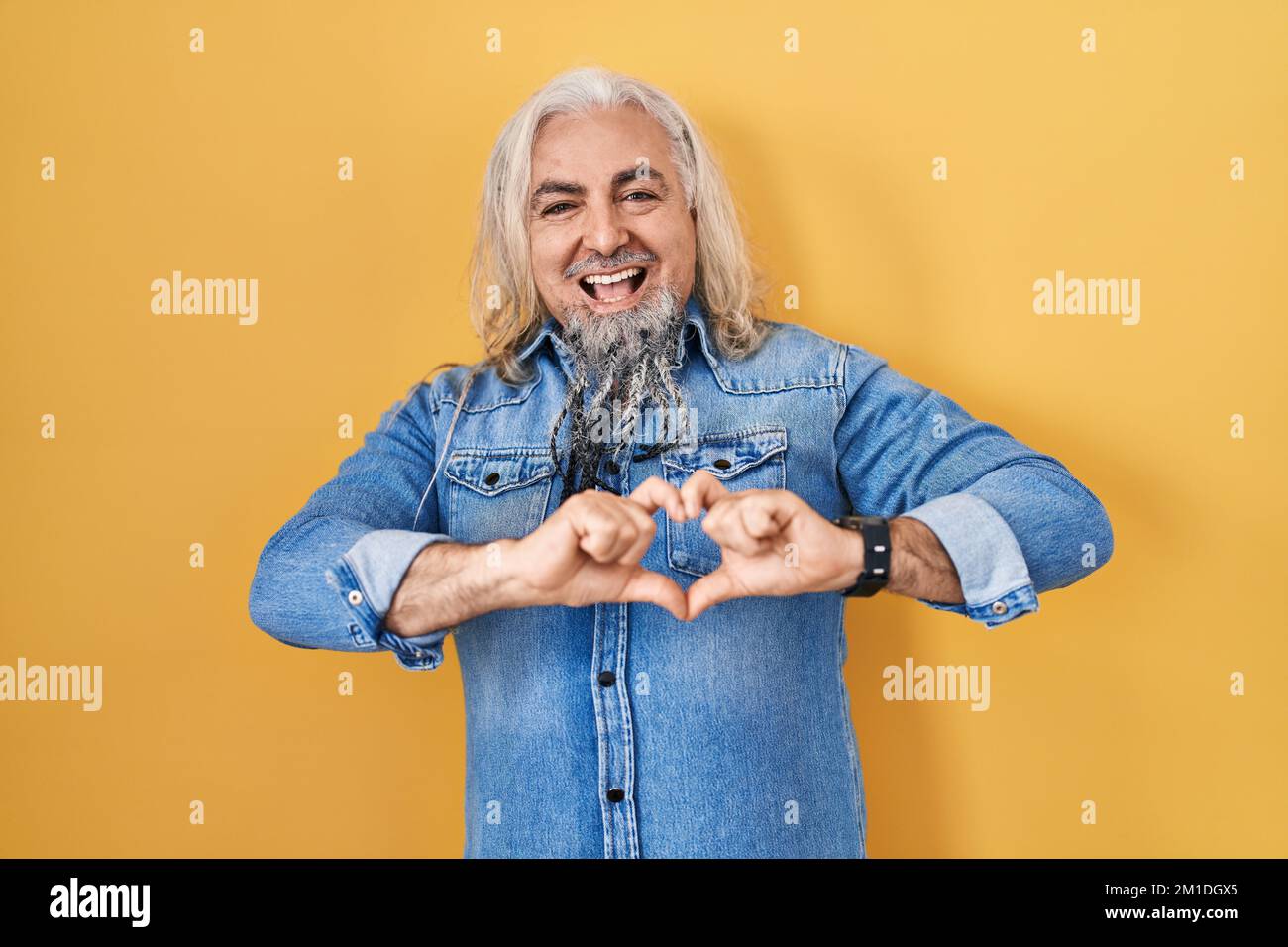 Middle age man with grey hair standing over yellow background smiling ...