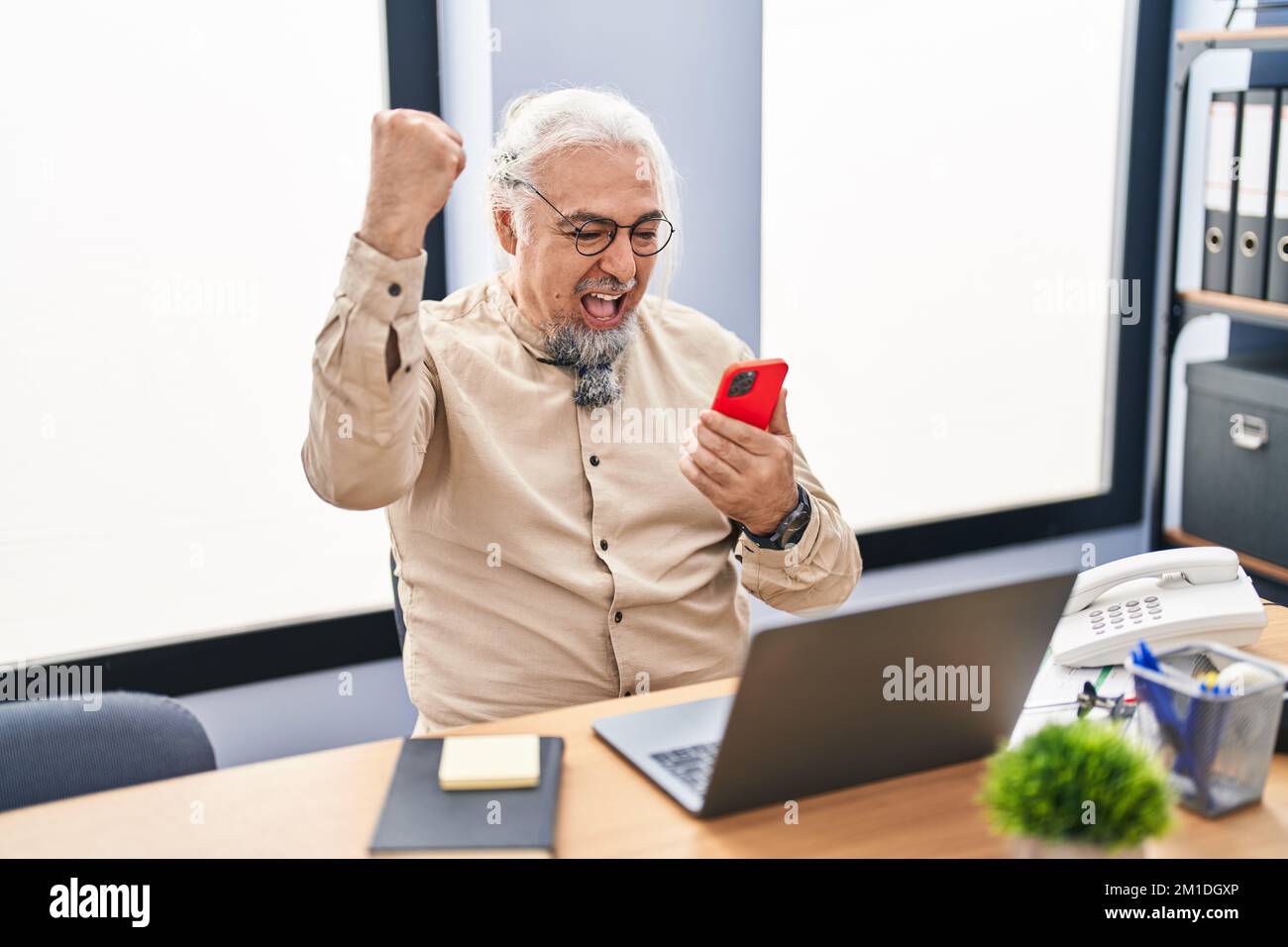 Middle age grey-haired man business worker using smartphone with winner ...