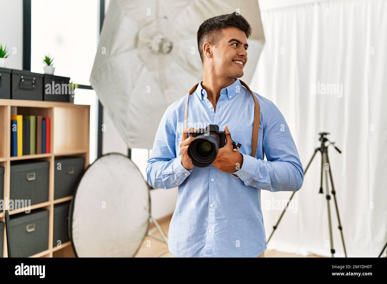 Young hispanic man photographer using professional camera at ...