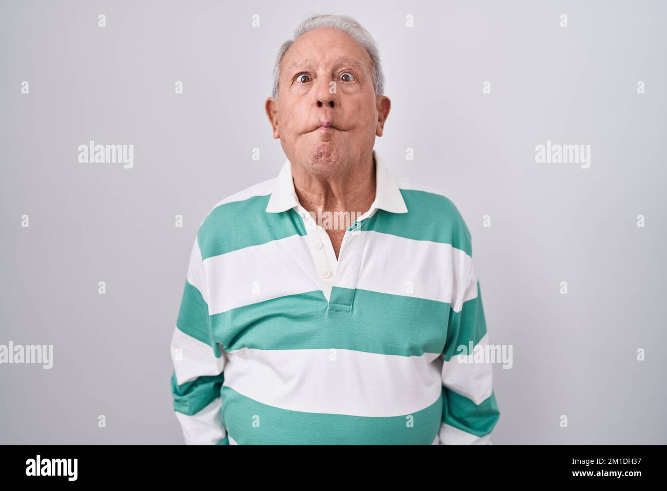 Senior man with grey hair standing over white background making fish ...