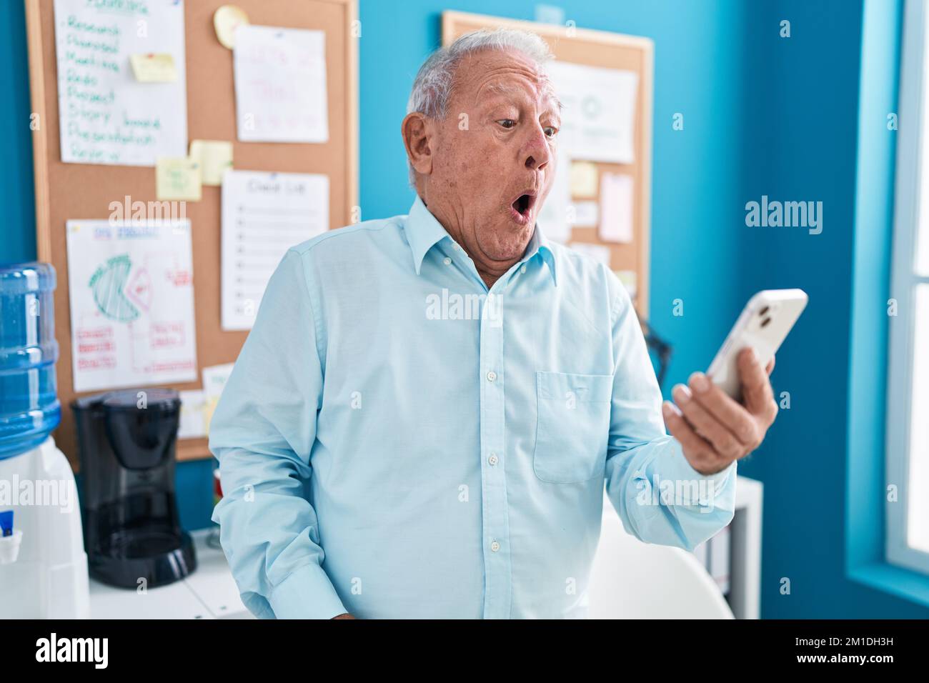 Senior man with grey hair working at the office doing video call with ...