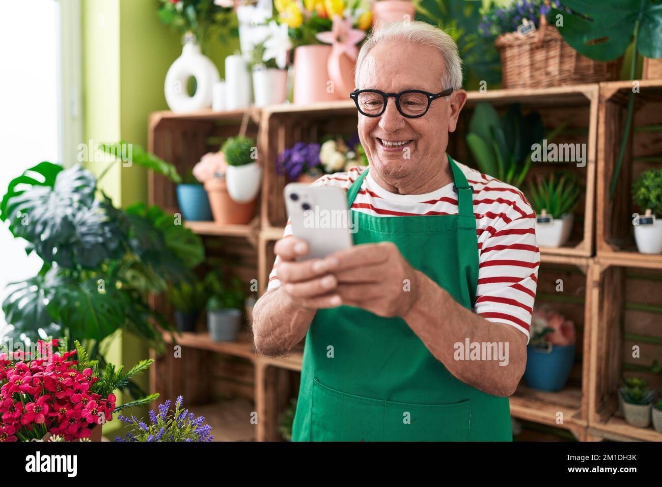 Middle age grey-haired man florist smiling confident using smartphone ...