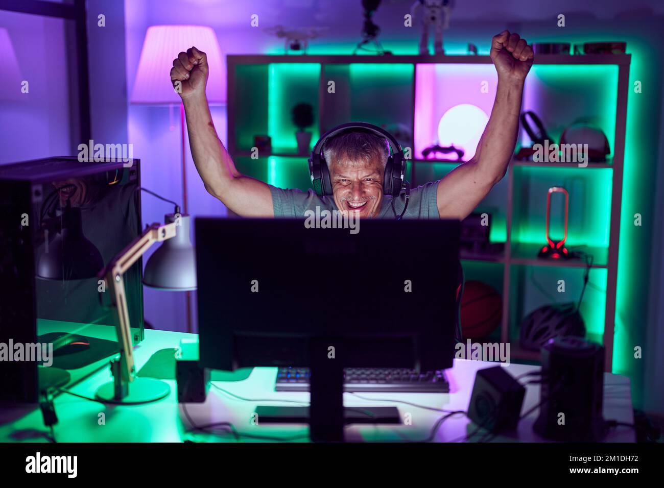 Middle age grey-haired man streamer playing video game using computer ...