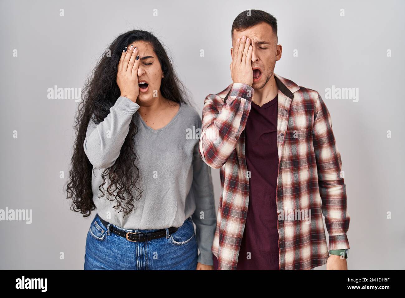 Young hispanic couple standing over white background yawning tired ...