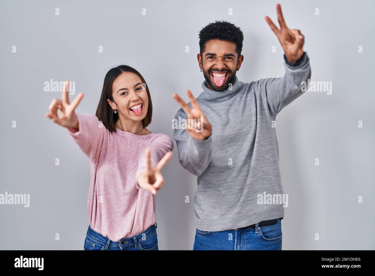 Young hispanic couple standing together smiling with tongue out showing ...