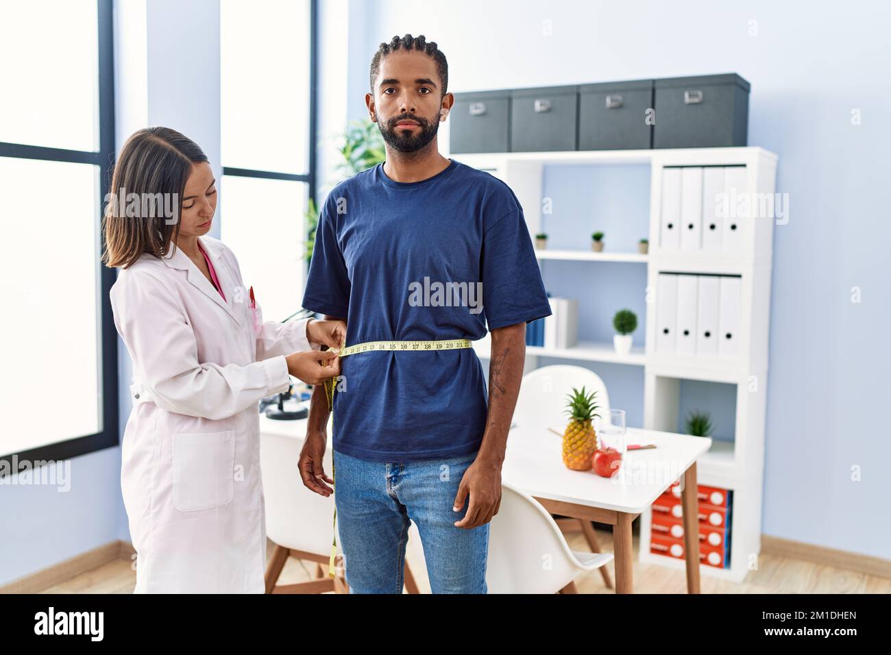 Dietitian at the clinic using tape measure measuring waist of client ...