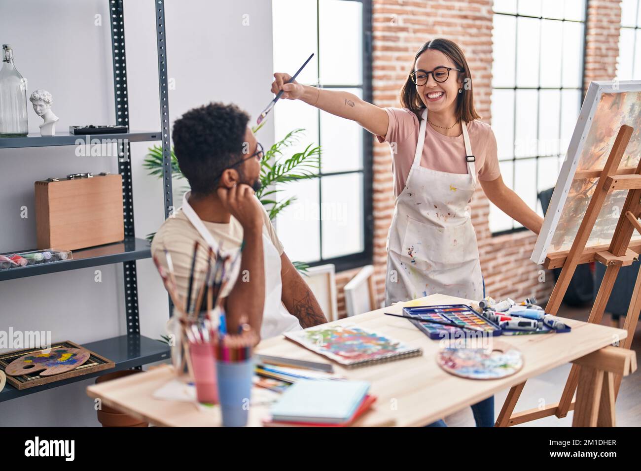 Man and woman artists smiling confident drawing on notebook at art ...
