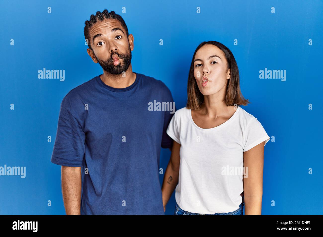 Young hispanic couple standing together making fish face with lips ...