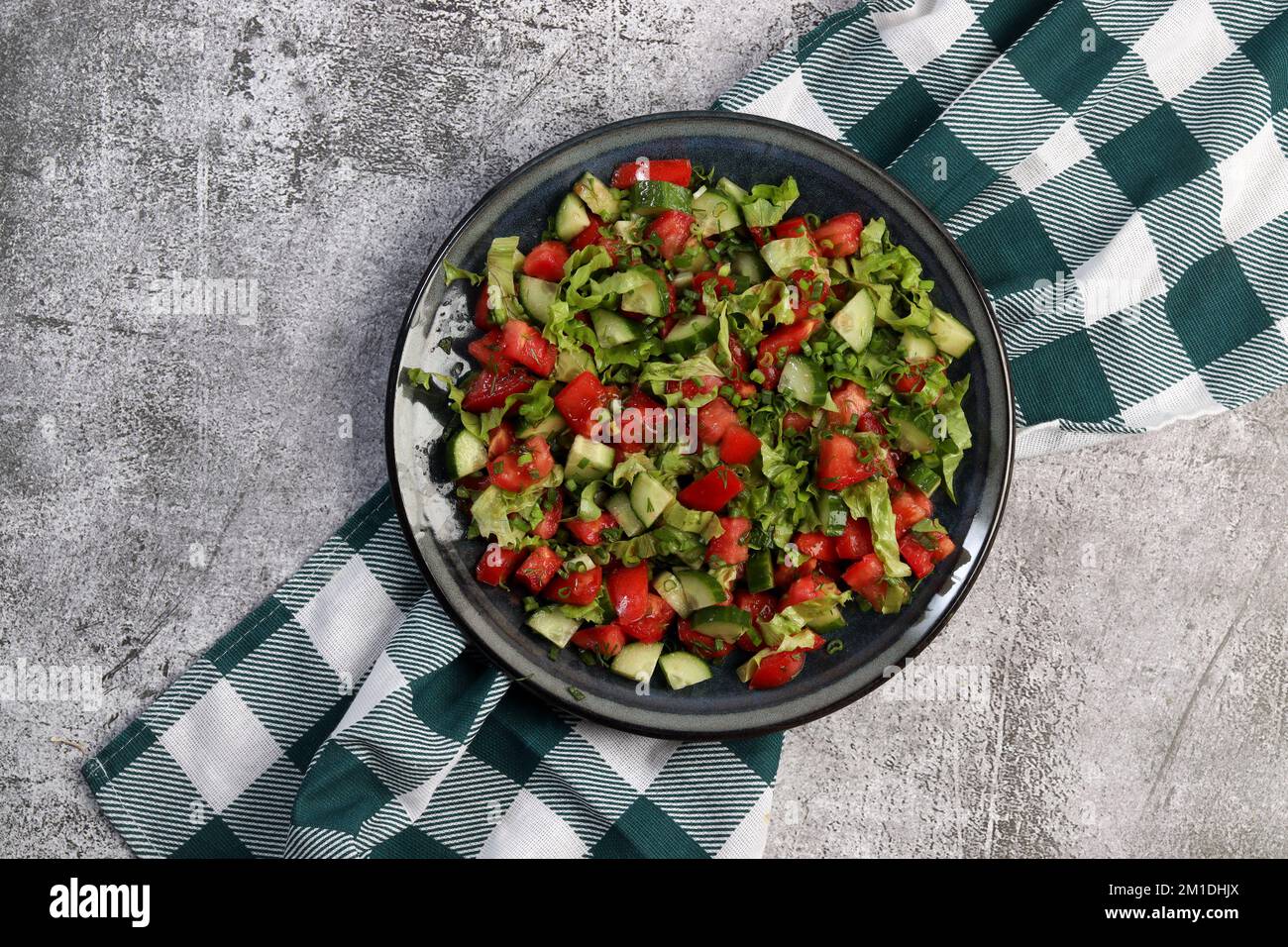 Vegetarian cucumber salad with lettuce, tomatoes and herbs on a round ...