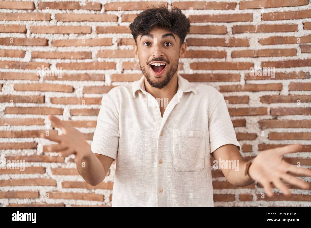 Arab man with beard standing over bricks wall background smiling ...