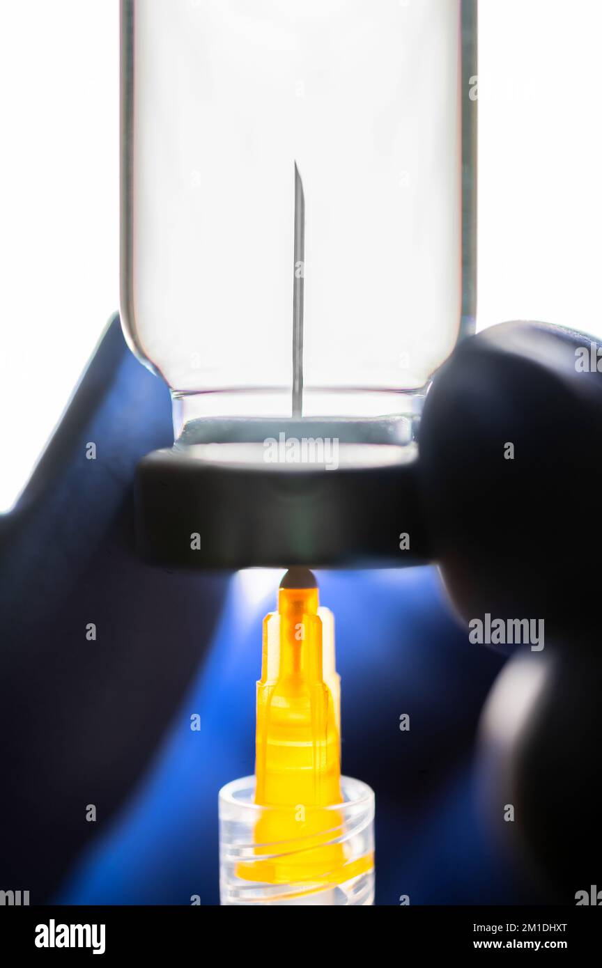 Syringe in an injection bottle against white background Stock Photo - Alamy