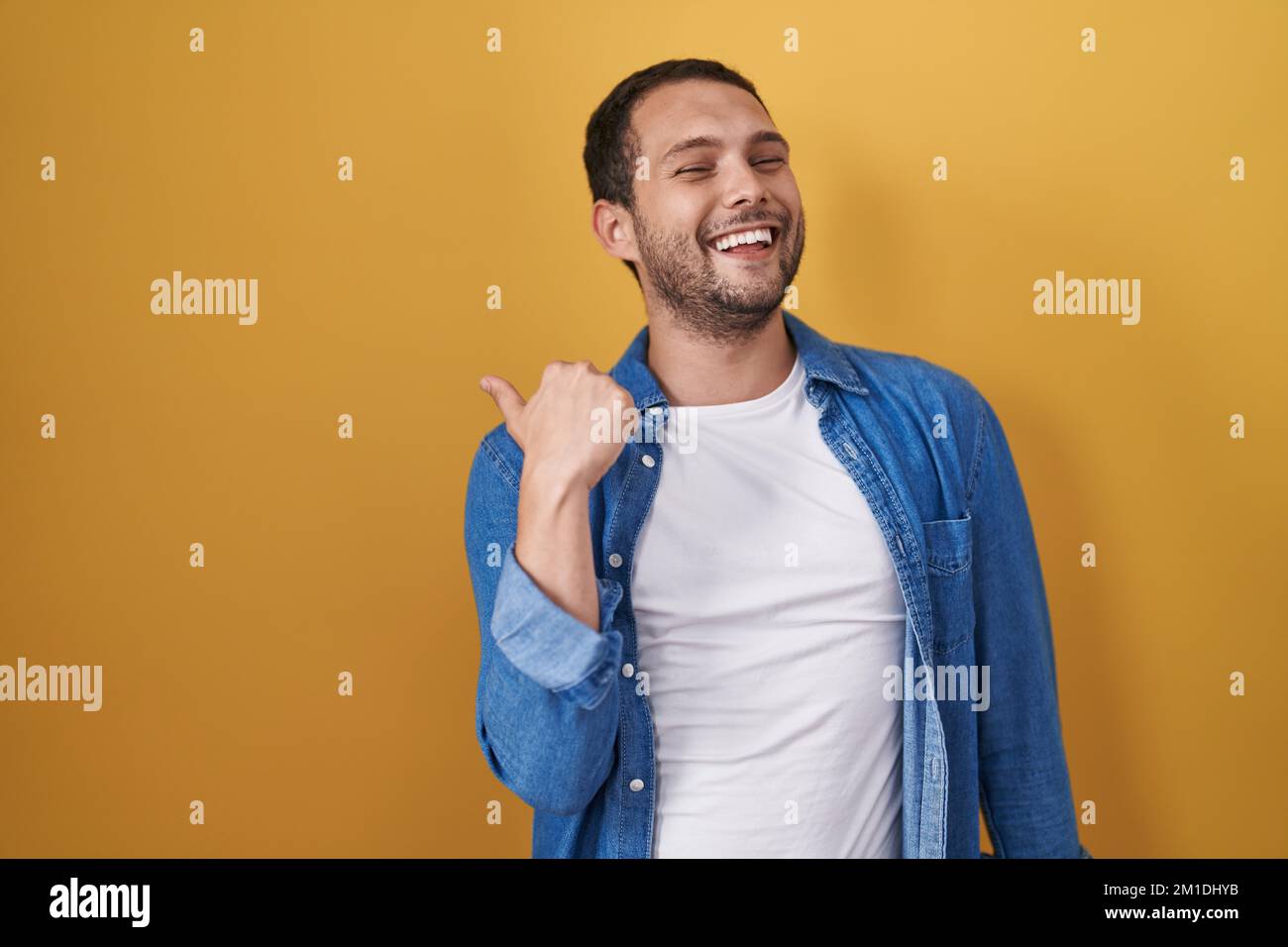 Hispanic man standing over yellow background smiling with happy face ...