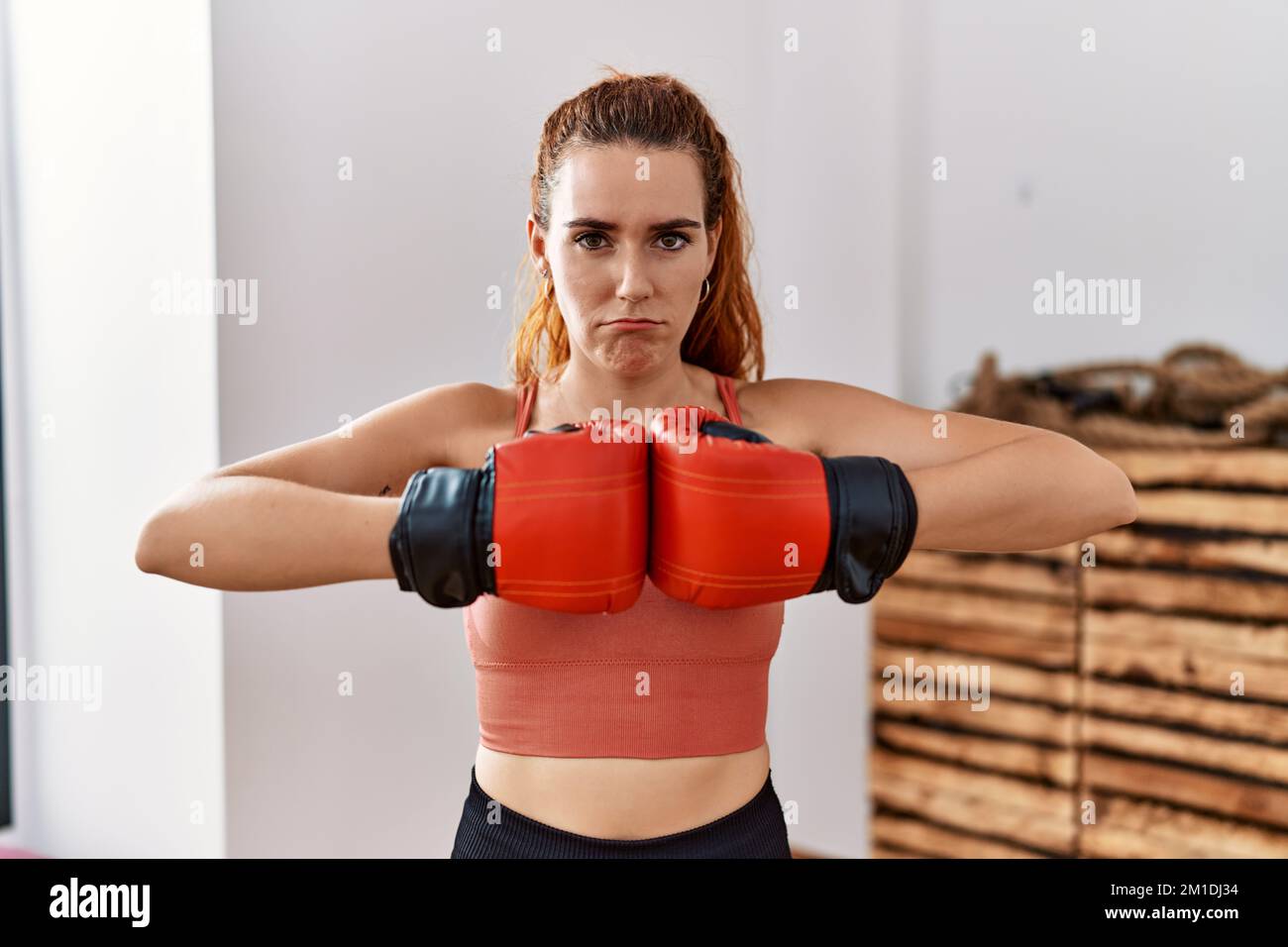 Young redhead woman using boxing gloves depressed and worry for ...