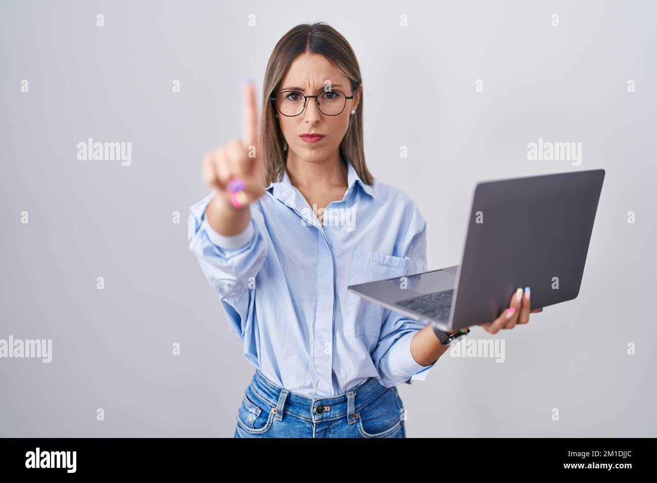 Young woman working using computer laptop pointing with finger up and ...