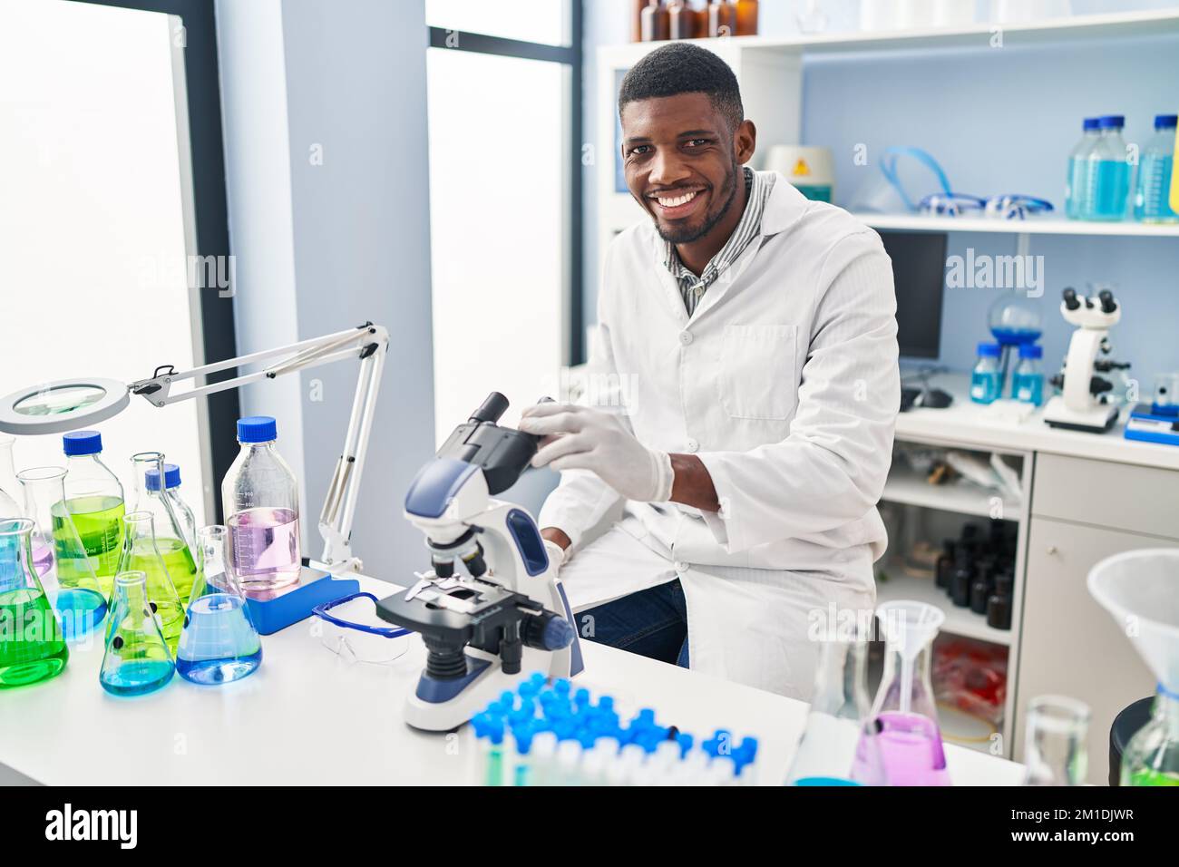 African american man working at scientist laboratory looking positive ...