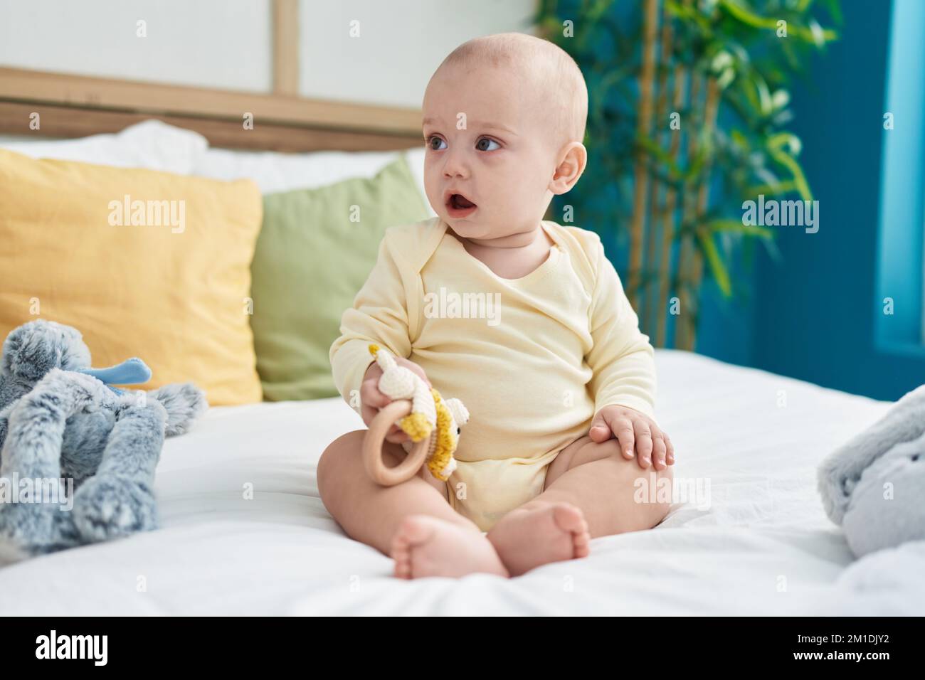 Adorable caucasian baby holding toy sitting on bed at bedroom Stock ...