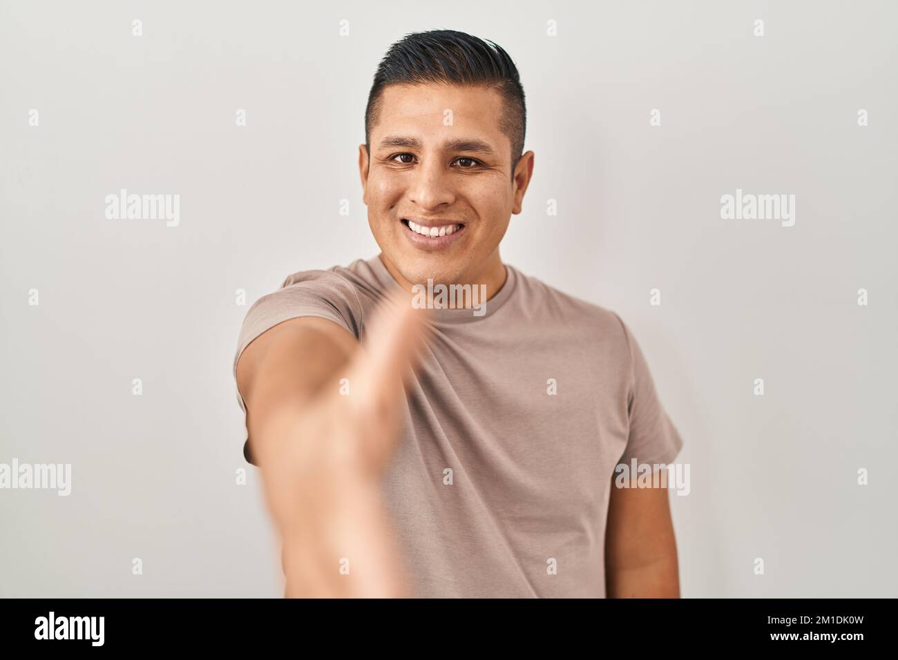 Hispanic young man standing over white background smiling friendly ...
