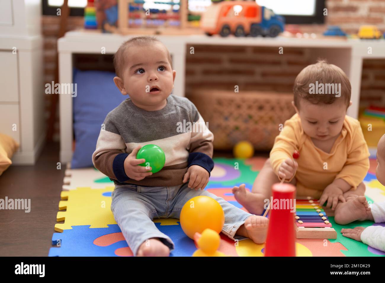 Two toddlers playing with ball and xylophone at kindergarten Stock ...