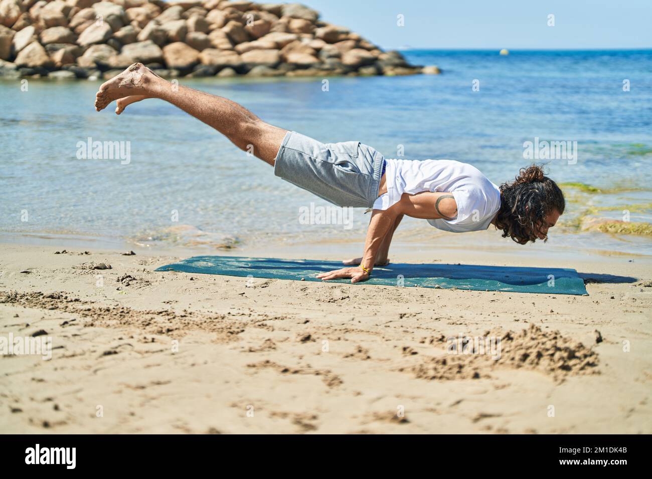 Young hispanic man doing yoga exercise at beach Stock Photo - Alamy