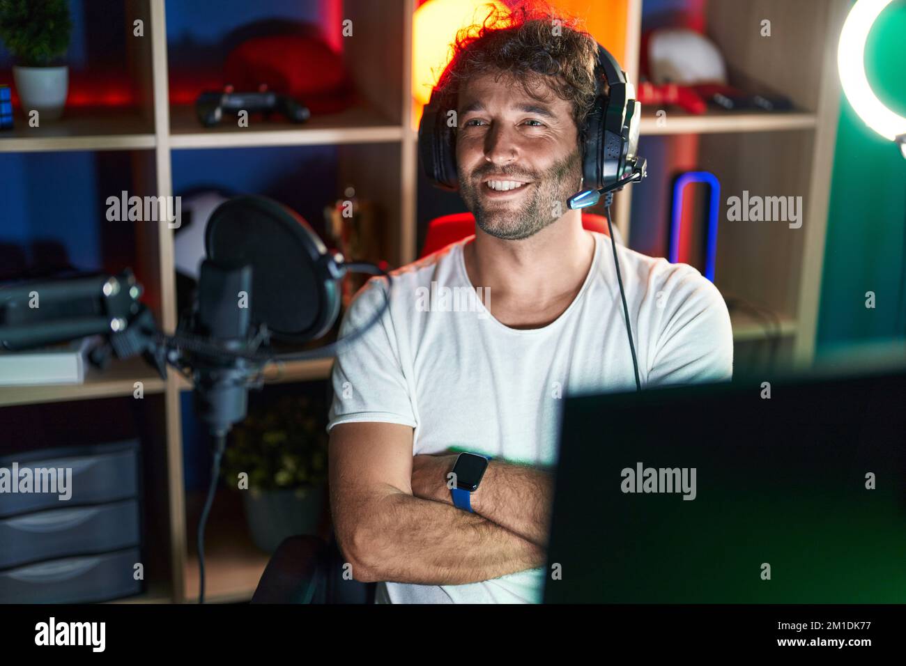 Young hispanic man streamer smiling confident sitting with arms crossed ...