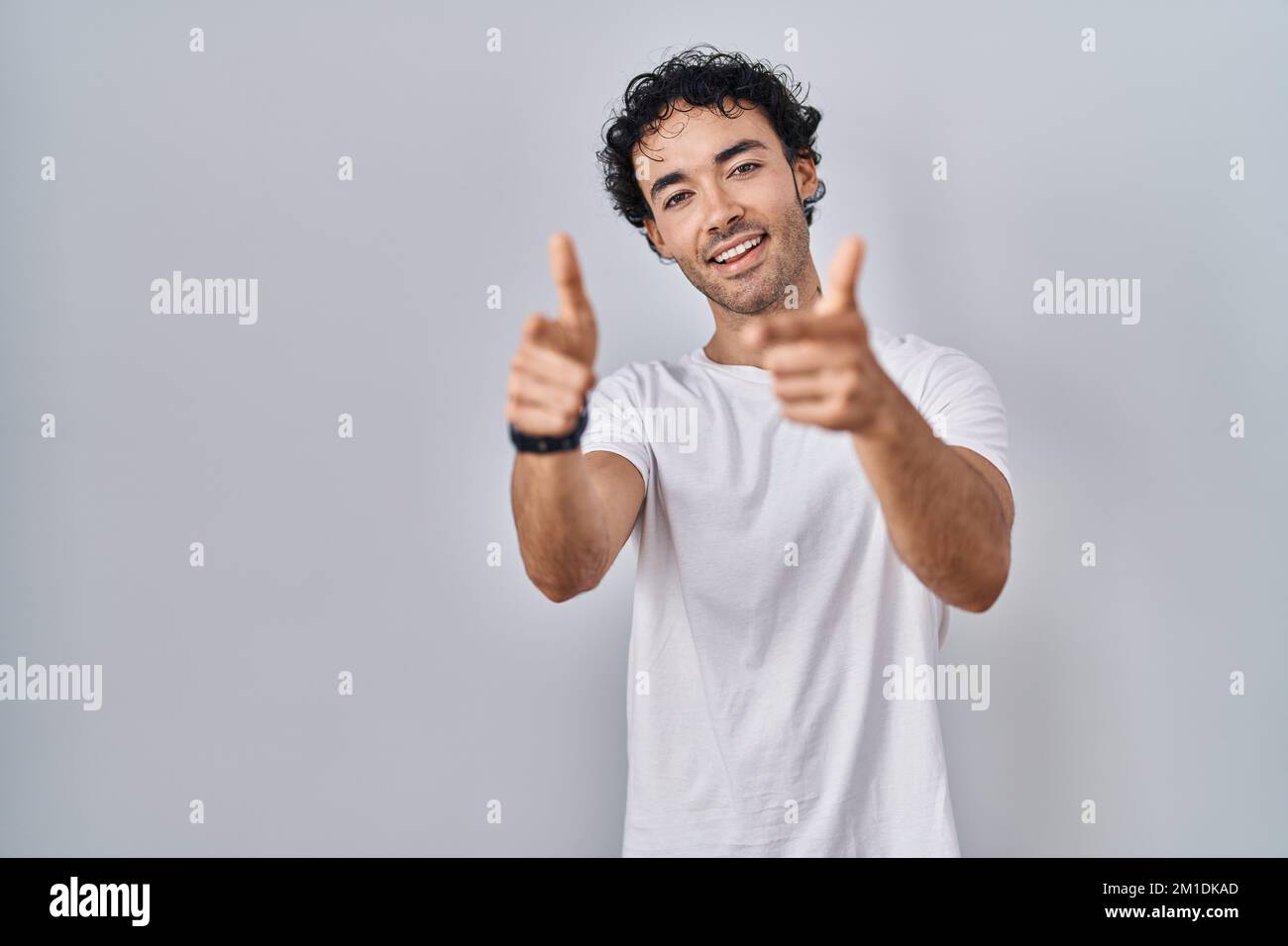Hispanic man standing over isolated background pointing fingers to ...