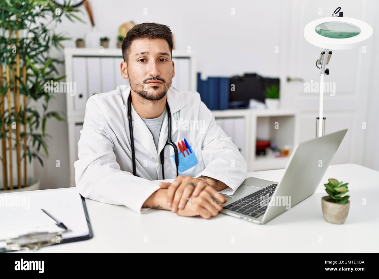 Young doctor working at the clinic using computer laptop depressed and ...