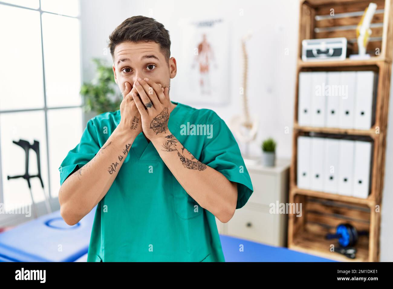 Young physiotherapist man working at pain recovery clinic laughing and ...
