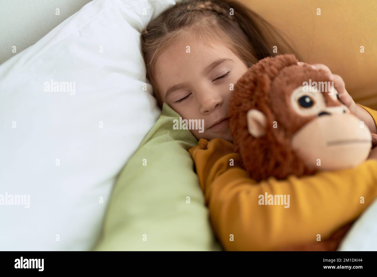 Adorable hispanic girl hugging monkey doll sleeping at bedroom Stock ...