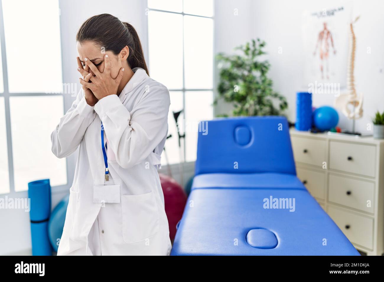 Young doctor woman working at pain recovery clinic with sad expression ...
