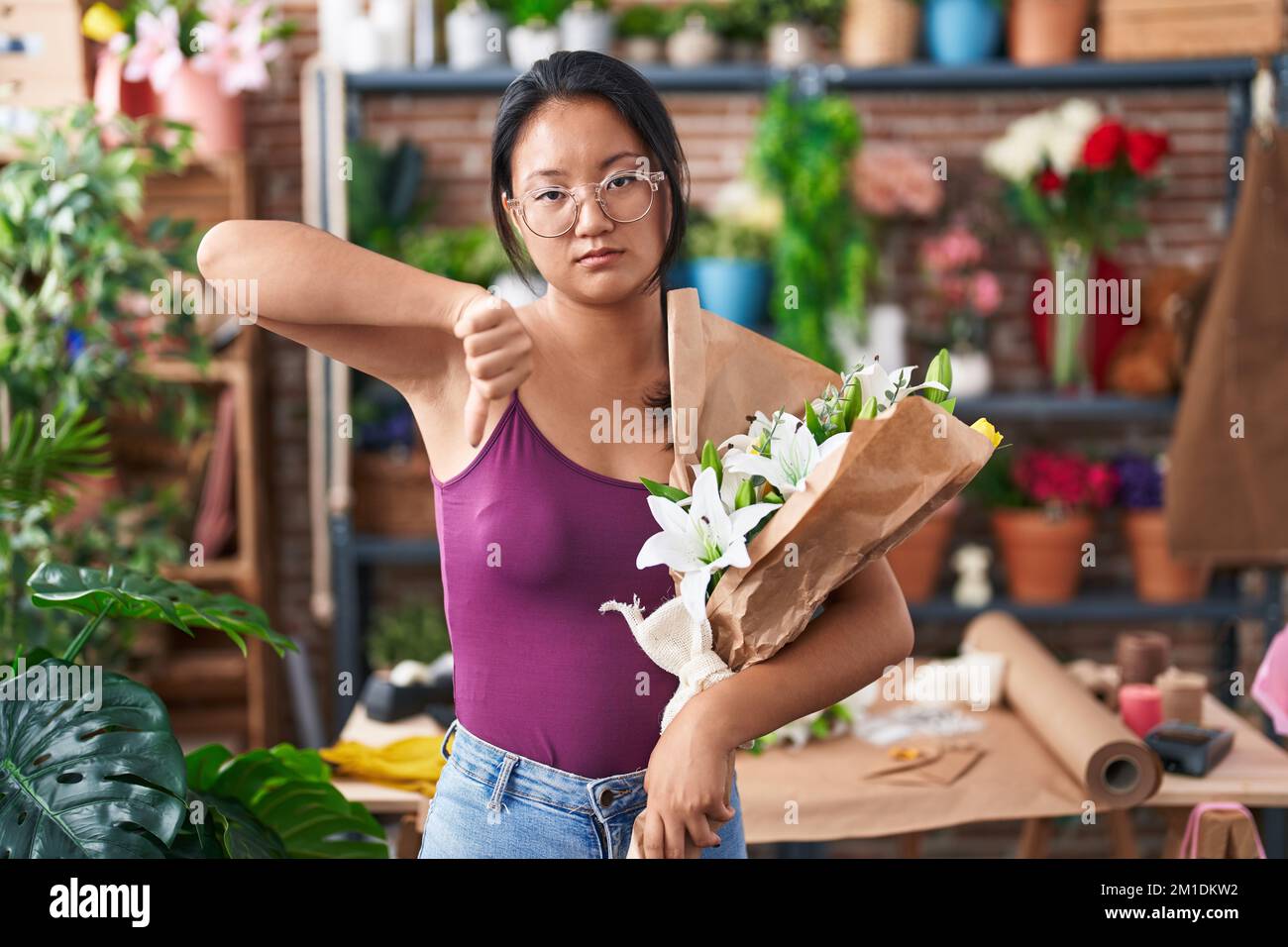 Asian young woman at florist shop holding bouquet of flowers with angry ...