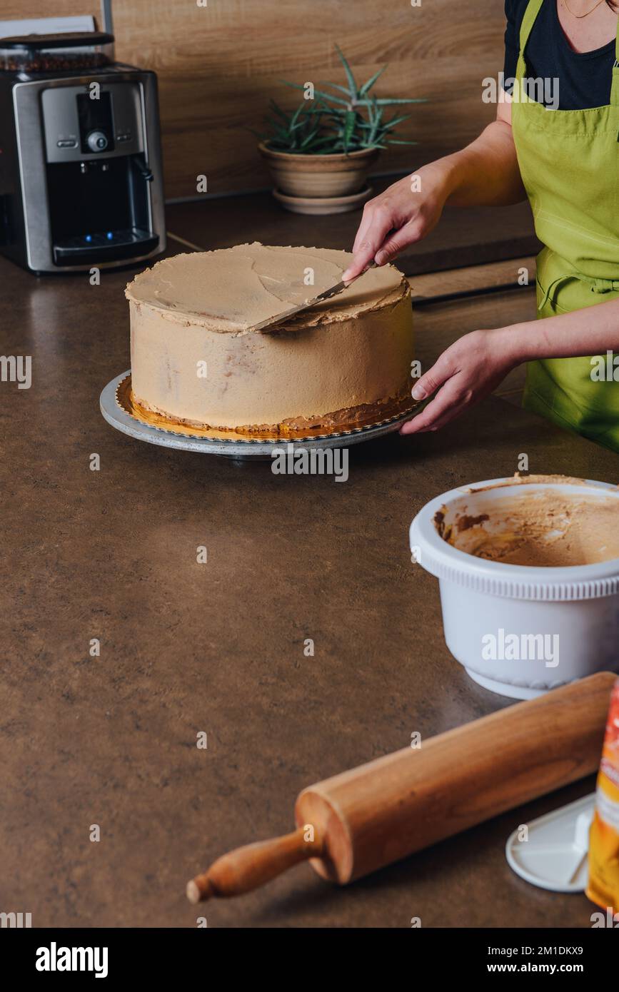 Unrecognisable woman decorating a delicious layered sponge cake with ...