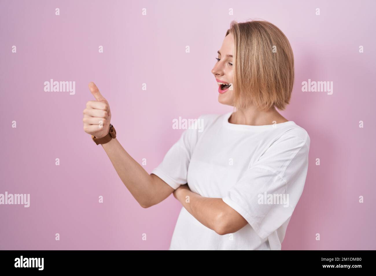 Young caucasian woman standing over pink background looking proud ...