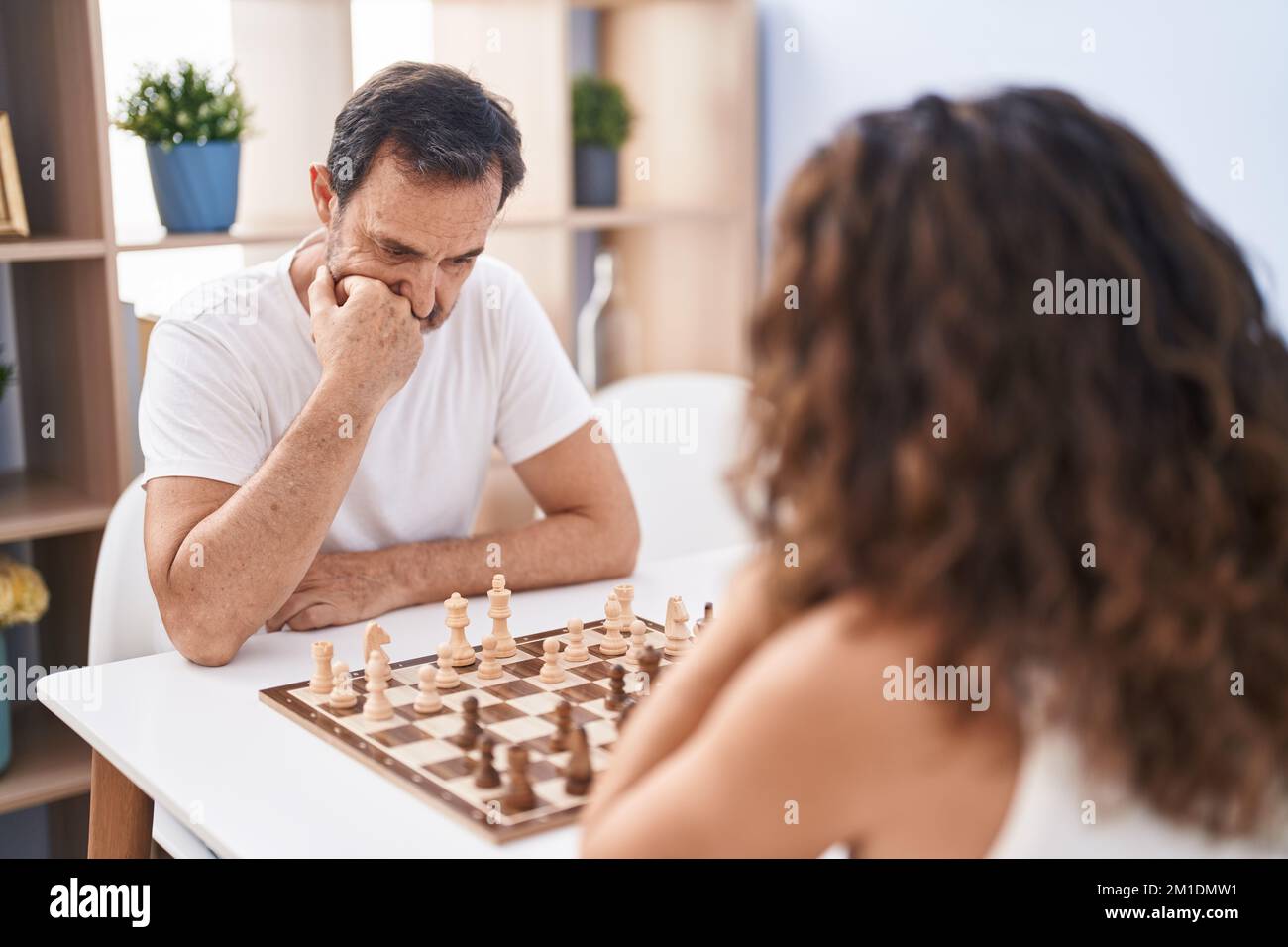 Man and woman playing chess game sitting on table at home Stock Photo ...