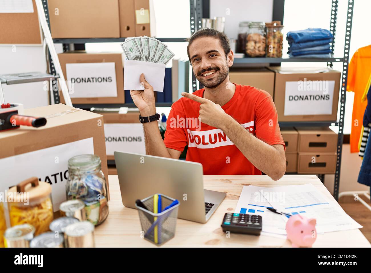 Young hispanic man holding money at donations stand smiling happy ...