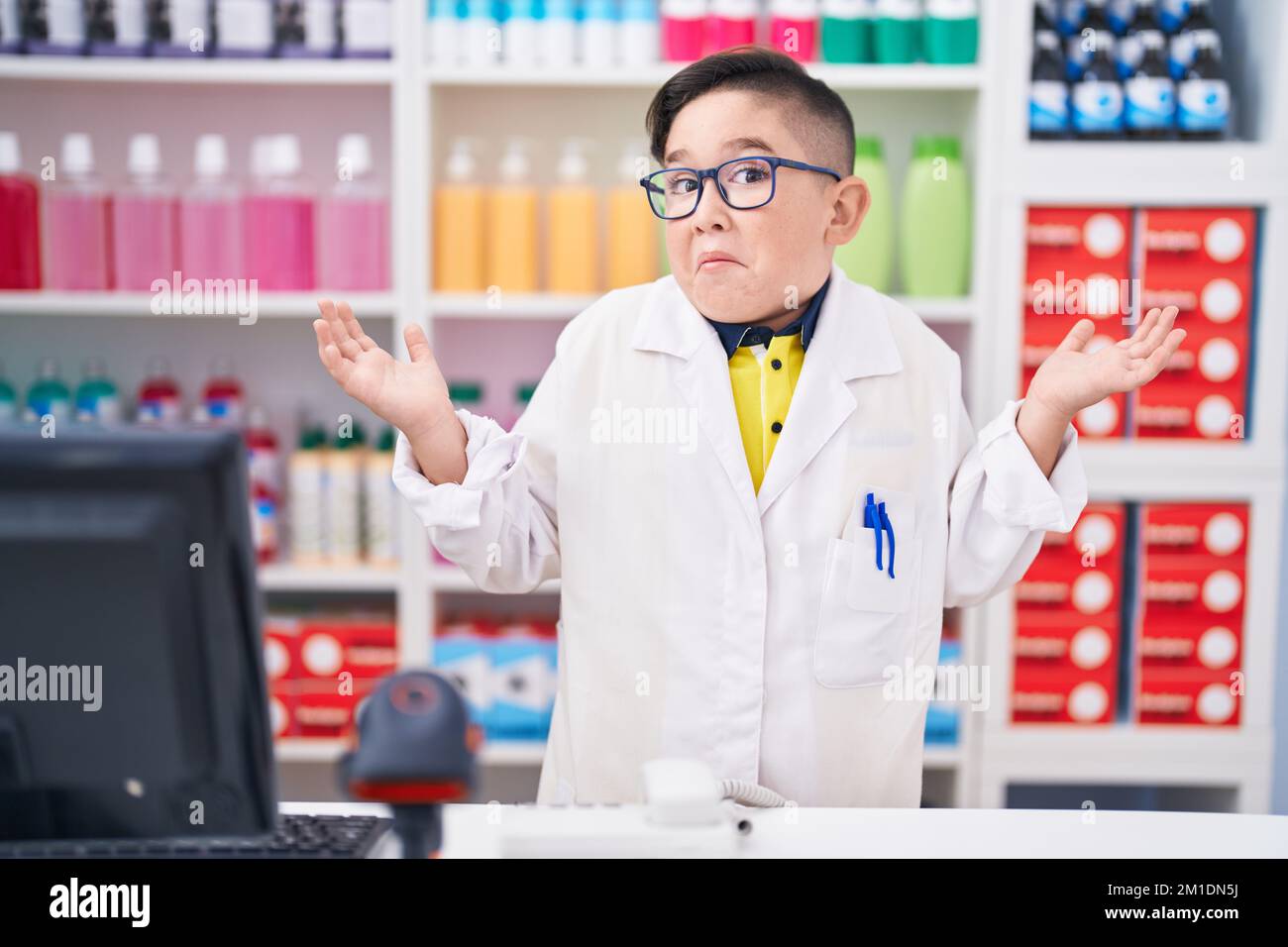 Young hispanic kid working at pharmacy drugstore shouting and screaming ...