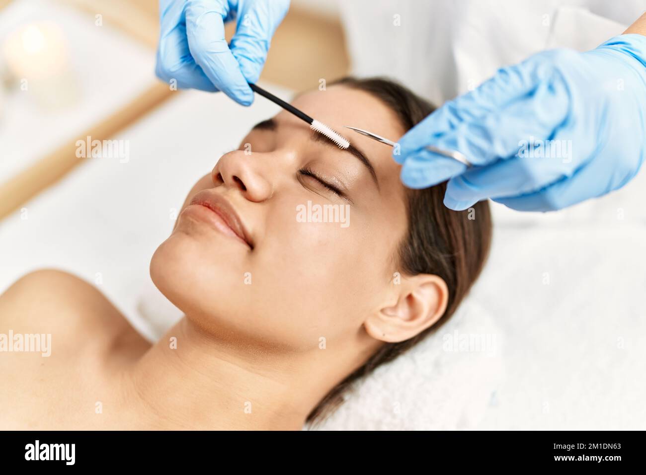 Young latin woman relaxed having eyebrows treatment at beauty center ...