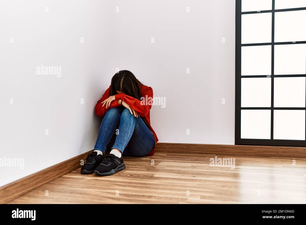 Young latin woman sitting on the floor crying at empty room Stock Photo ...