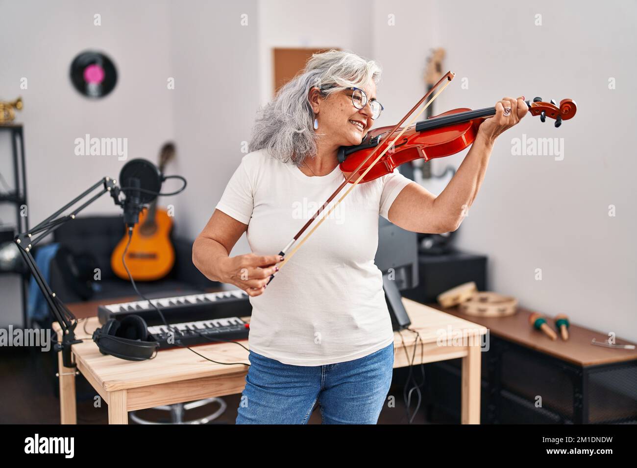 Middle age woman musician playing violin at music studio Stock Photo ...