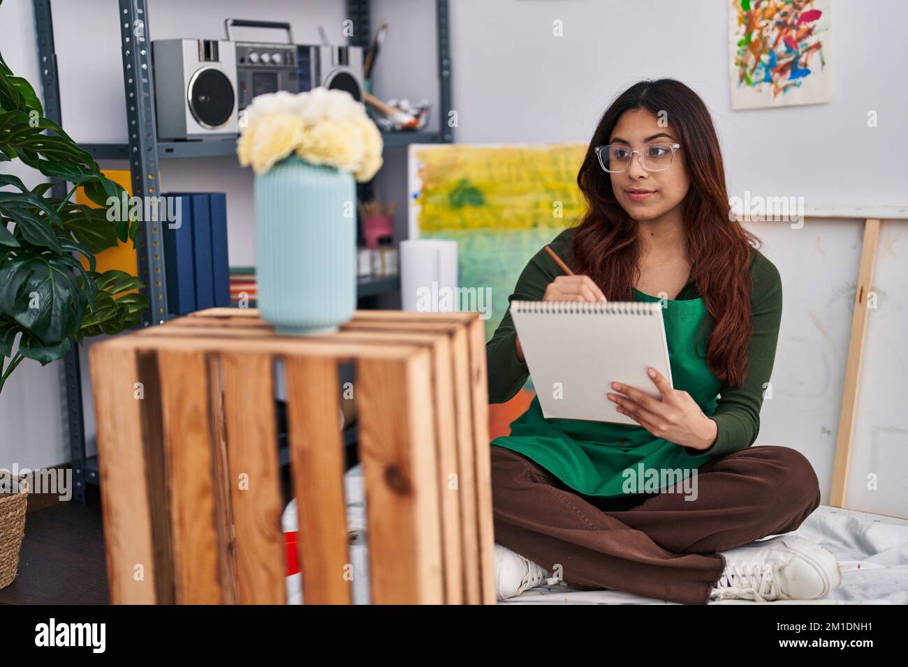 Young hispanic woman artist drawing on notebook at art studio Stock ...