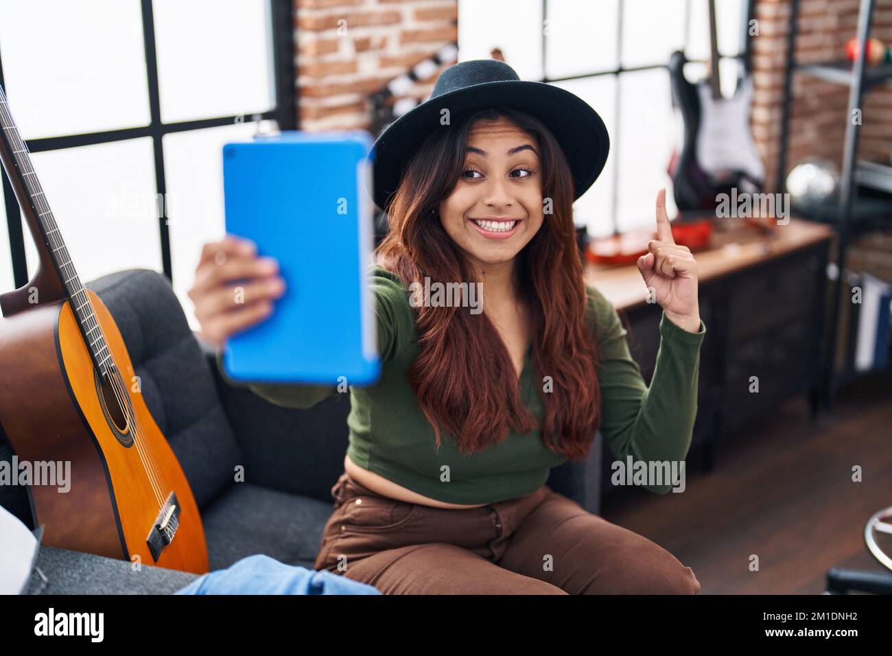 Hispanic young woman doing video call with tablet smiling with an idea ...