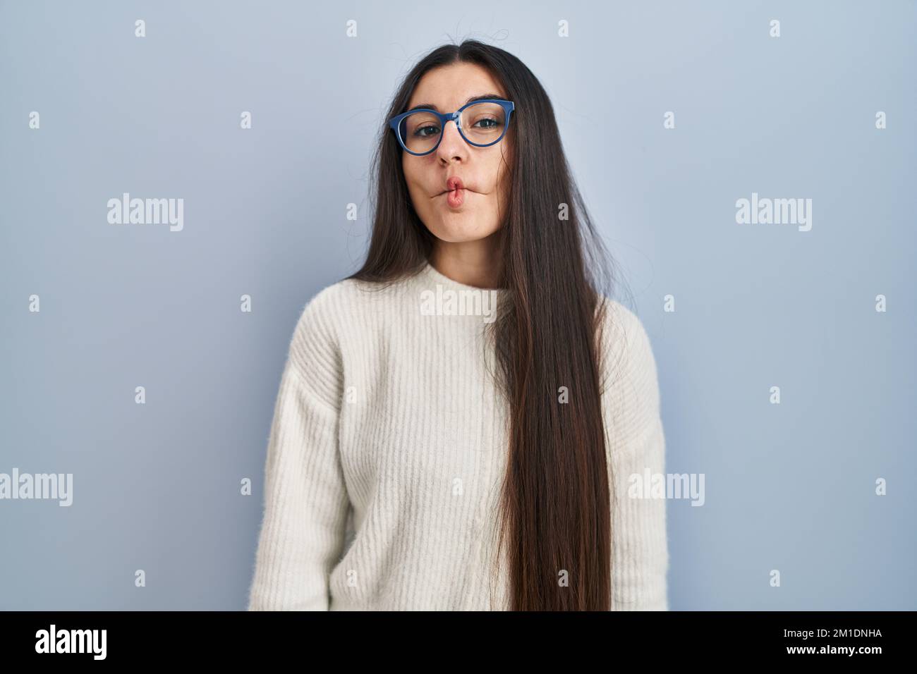 Young hispanic woman wearing casual sweater over blue background making ...
