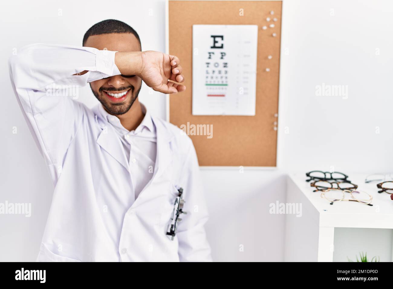 African american optician man standing by eyesight test covering eyes ...