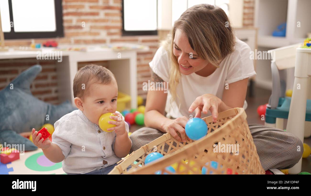 Mother and son sucking ball sitting on floor at kindergarten Stock ...
