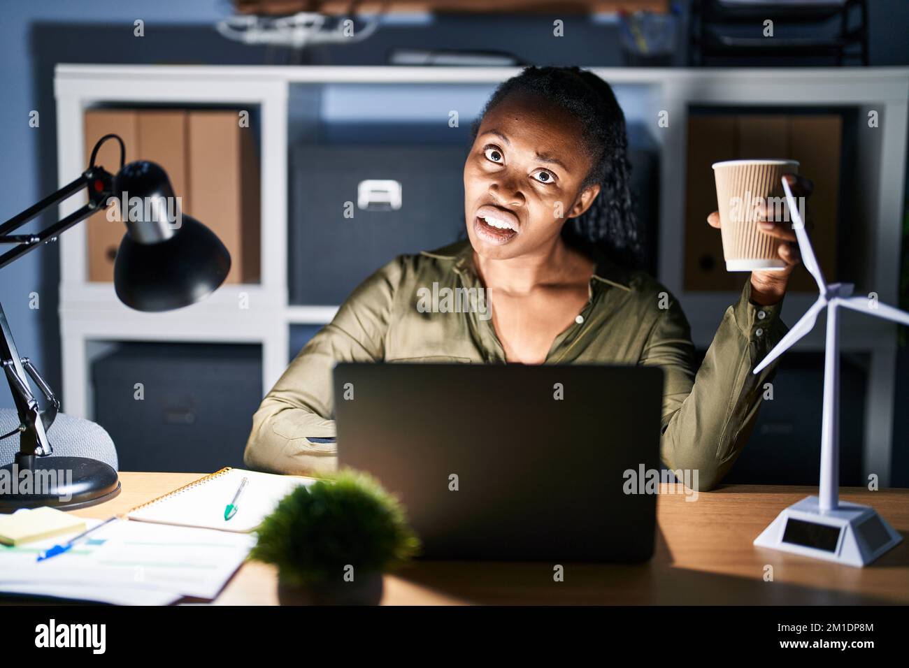 African woman working using computer laptop at night in shock face ...