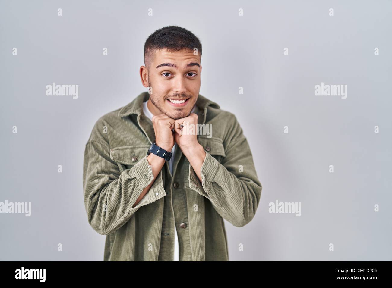 Young hispanic man standing over isolated background laughing nervous ...